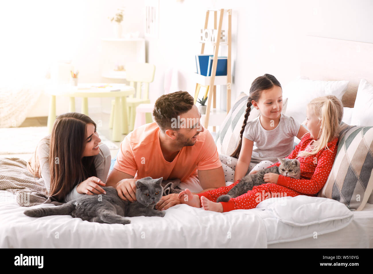 Happy family with cute cats on bed at home Stock Photo - Alamy