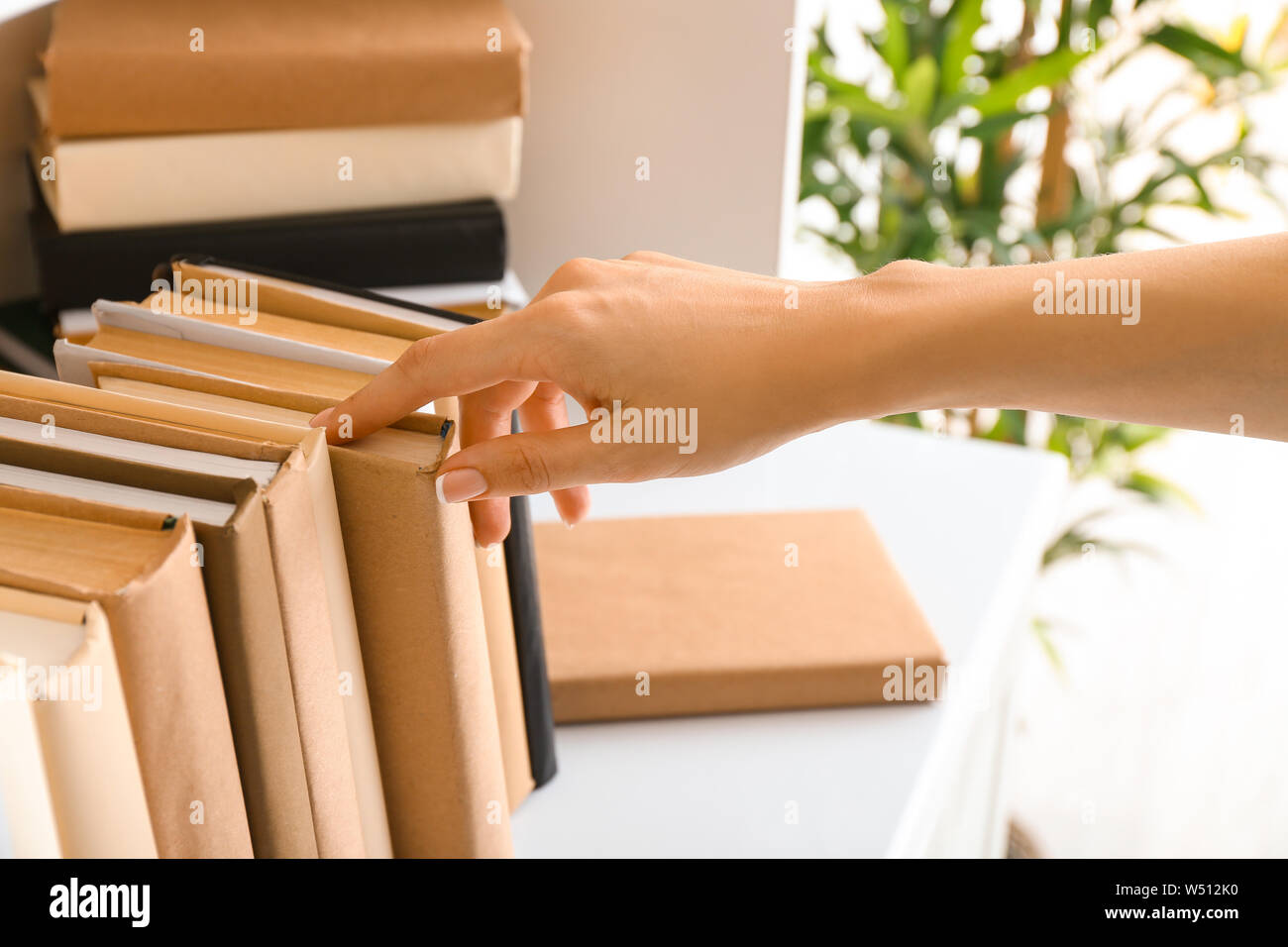 Woman taking book from shelf Stock Photo - Alamy
