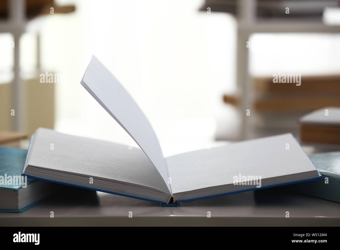 Open book on table in library Stock Photo - Alamy