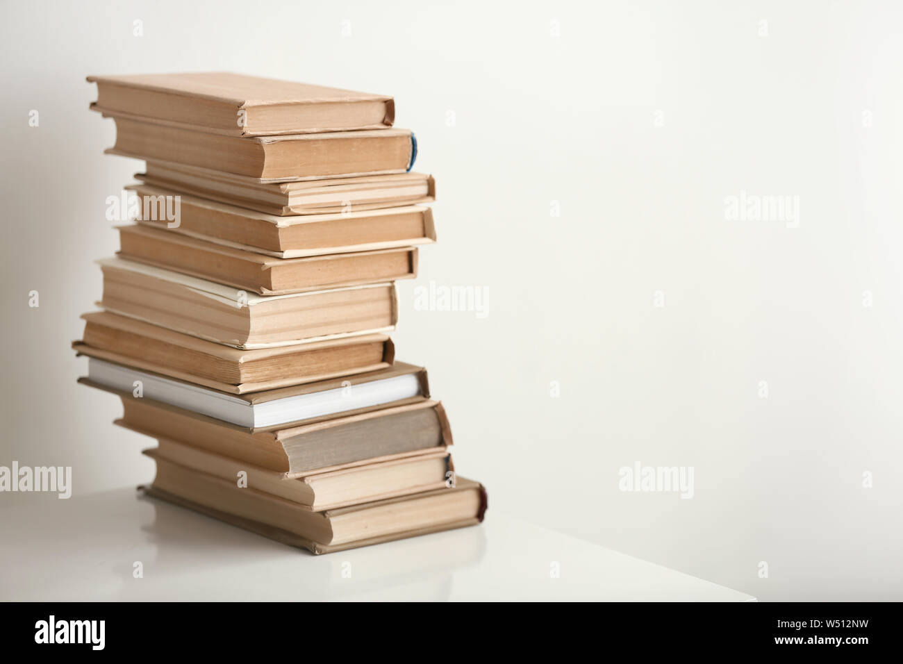 Stack of books on table against light background Stock Photo - Alamy