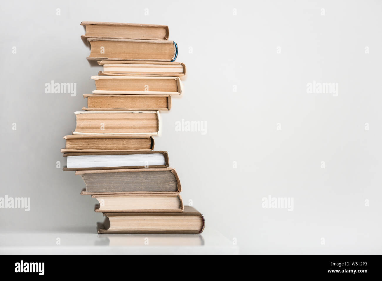 Stack of books on table against light background Stock Photo - Alamy