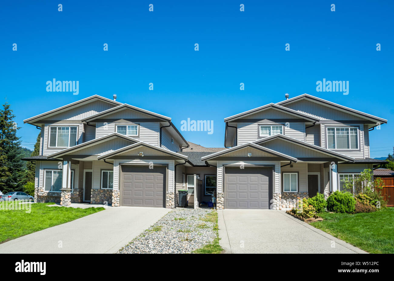 Residential duplex building with concrete drive ways and green lawns in ...