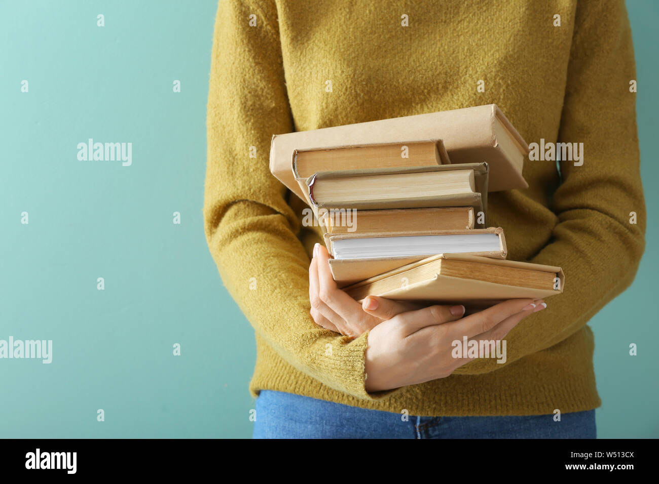 Woman with books on color background Stock Photo - Alamy