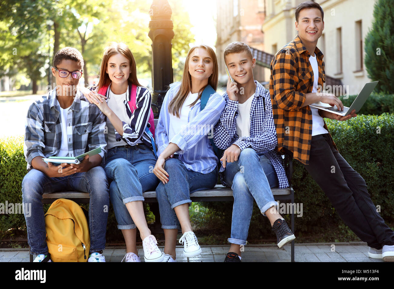 Young students sitting on bench outdoors Stock Photo - Alamy