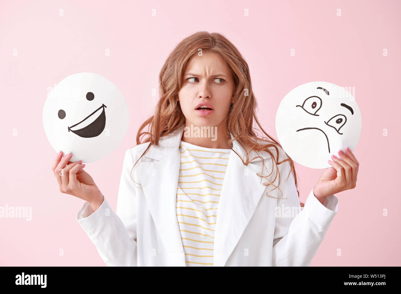 Portrait of confused young woman with emoticons on color background ...