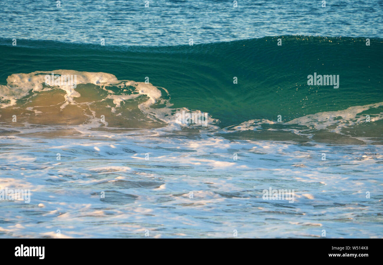 Waves rolling in to the beach with the afternoon sunlight shining ...
