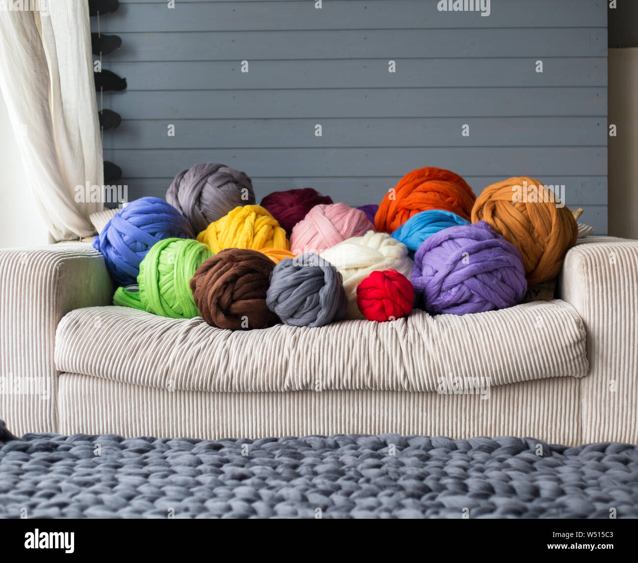 Merino wool balls in multicolour lying on white sofa with merino wool ...