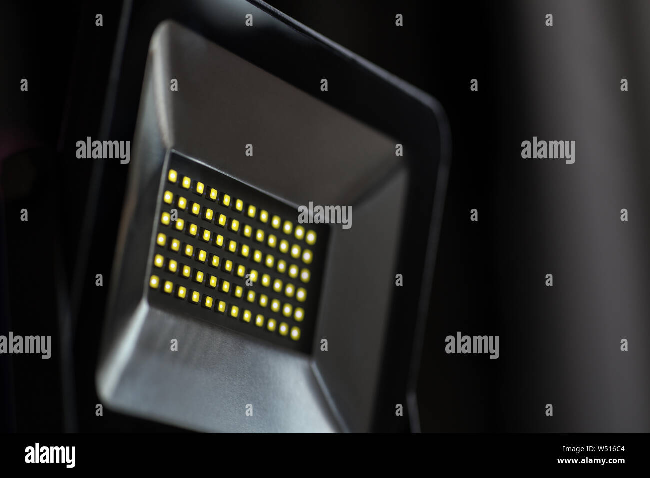 A rectangular diode spotlight of gray color in a dark room illuminates ...