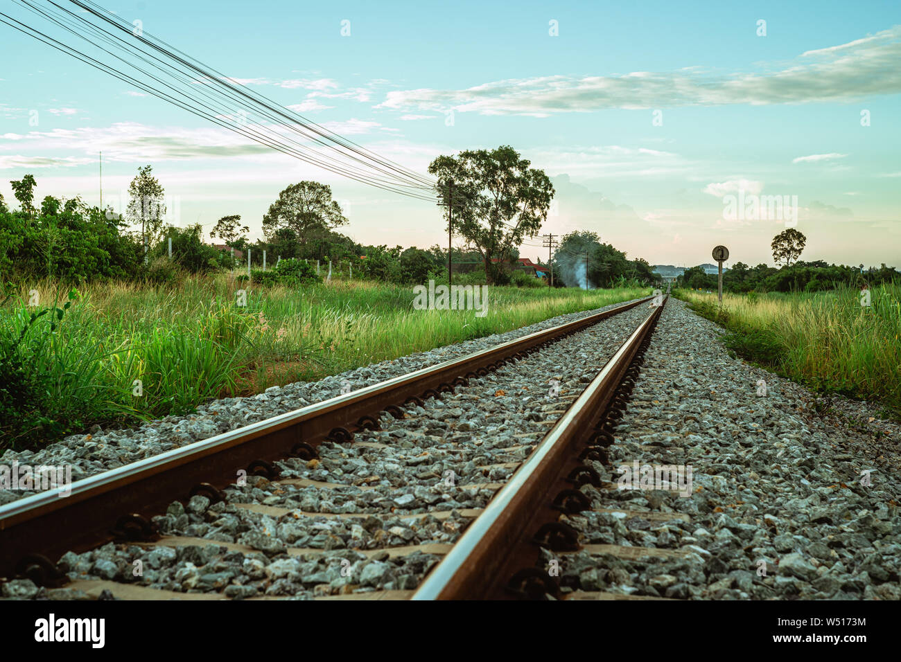Railway tracks with a green landscape with trees in Asia at sunset ...