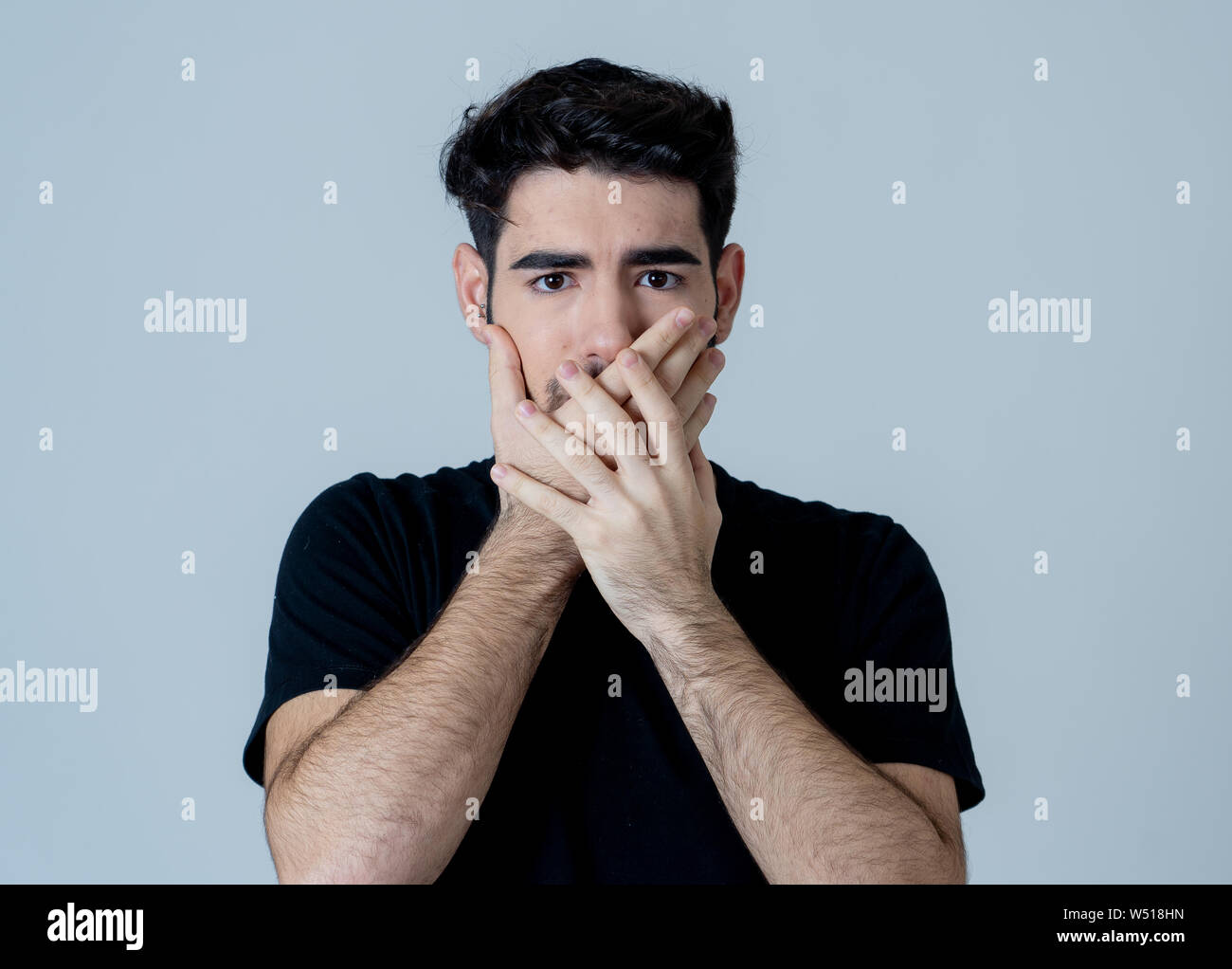 Young man feeling scared and shocked making fear anxiety gestures ...