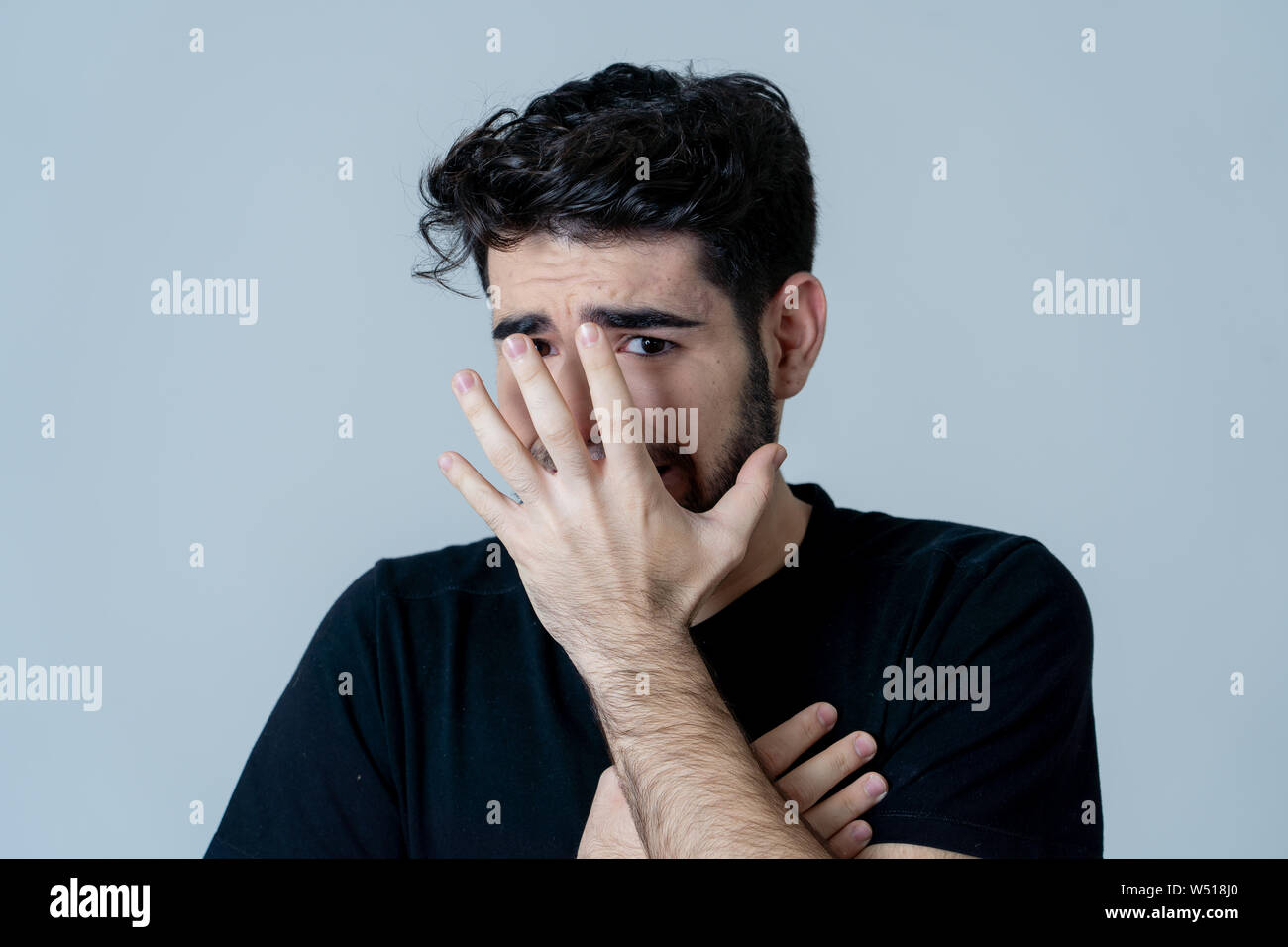 Young man feeling scared and shocked making fear anxiety gestures ...