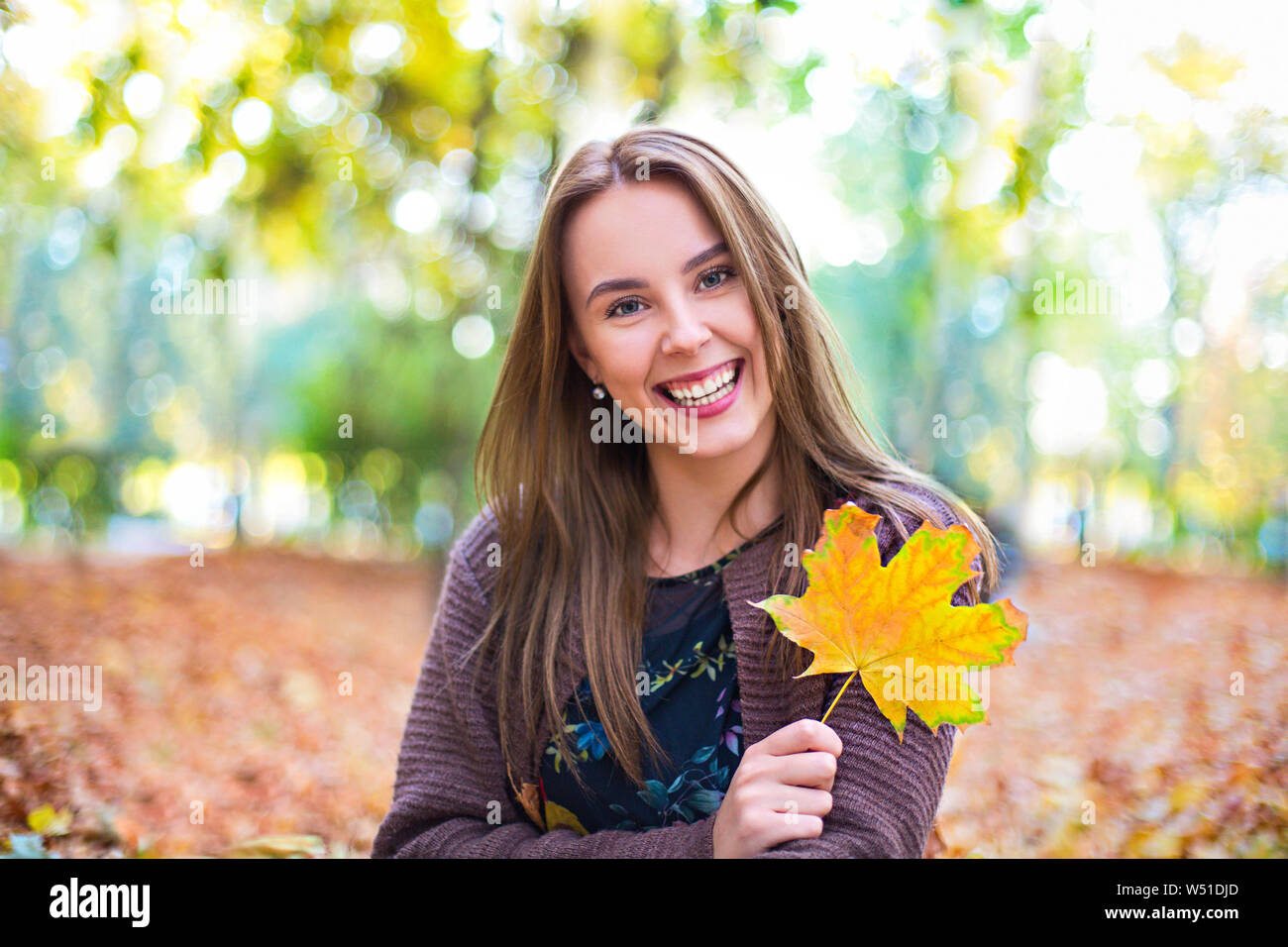Happy brunette girl posing in autumn park on yellow trees background ...
