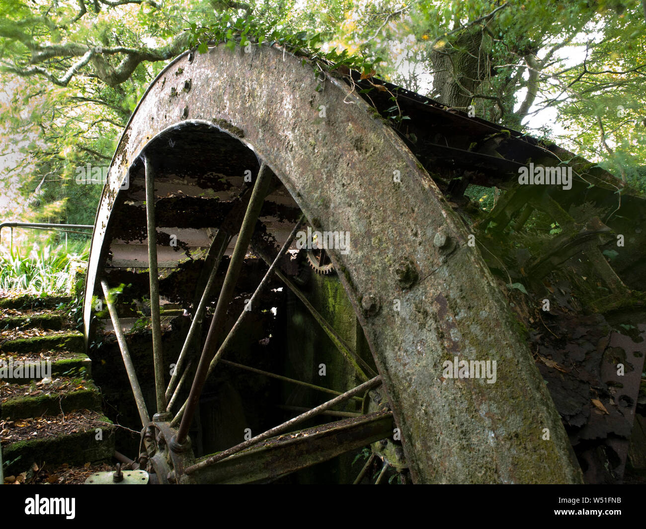An old and rusting metal water mill wheel showing inner cog and spokes ...