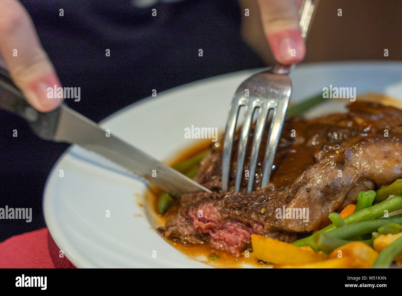 Human hand using spoon and fork while having beef steak Stock Photo - Alamy