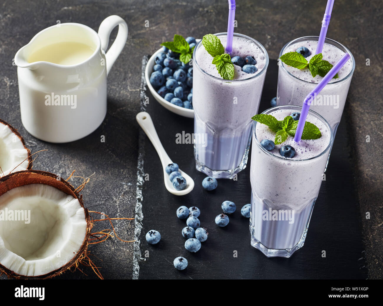 blueberry frothy milkshake of coconut milk in three glasses with straws ...