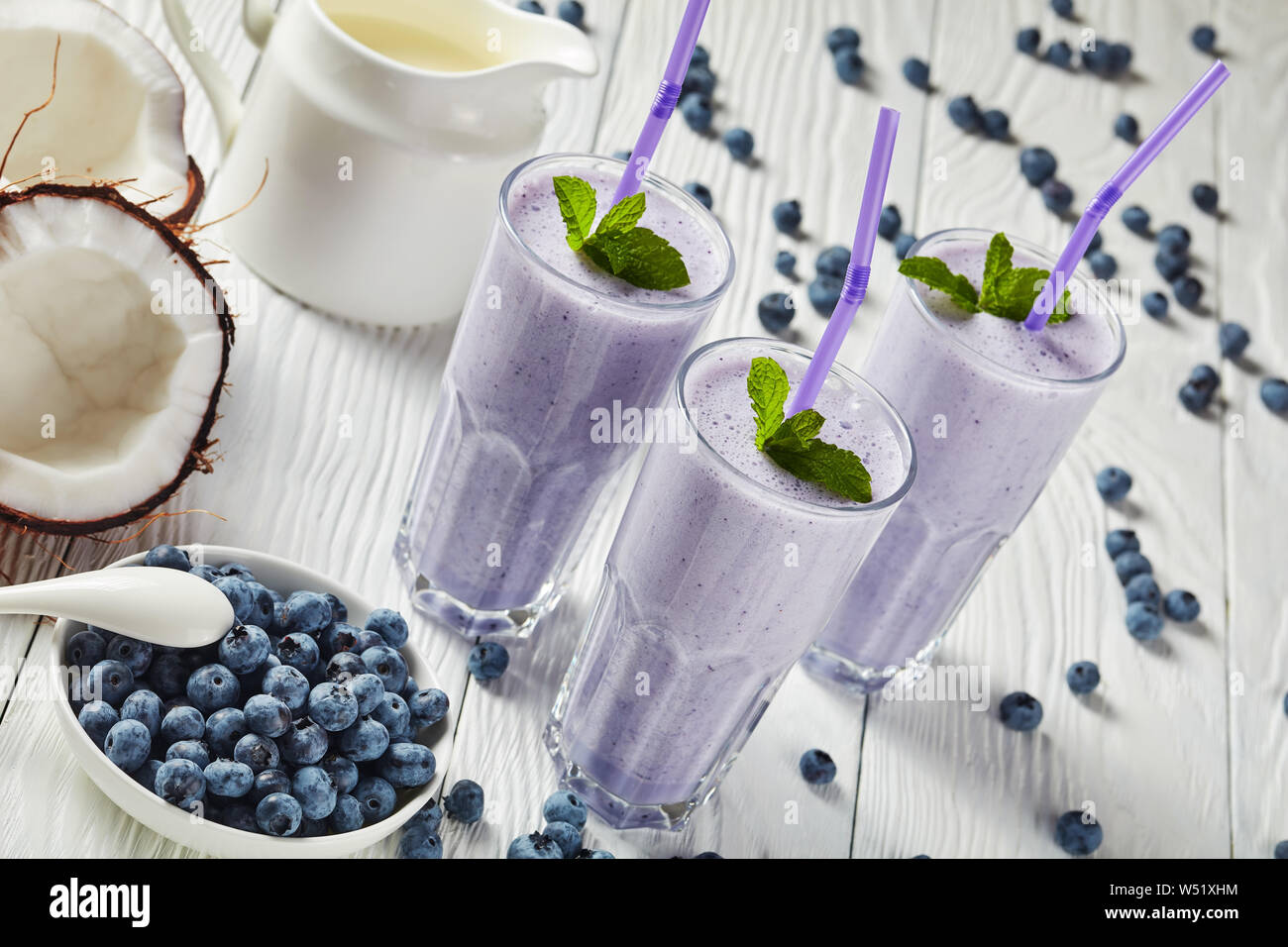 blueberry frothy milkshake of coconut milk in three glasses with straws ...