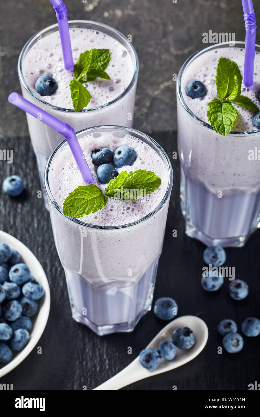 close-up of blueberry frothy milkshake of coconut milk in three glasses ...