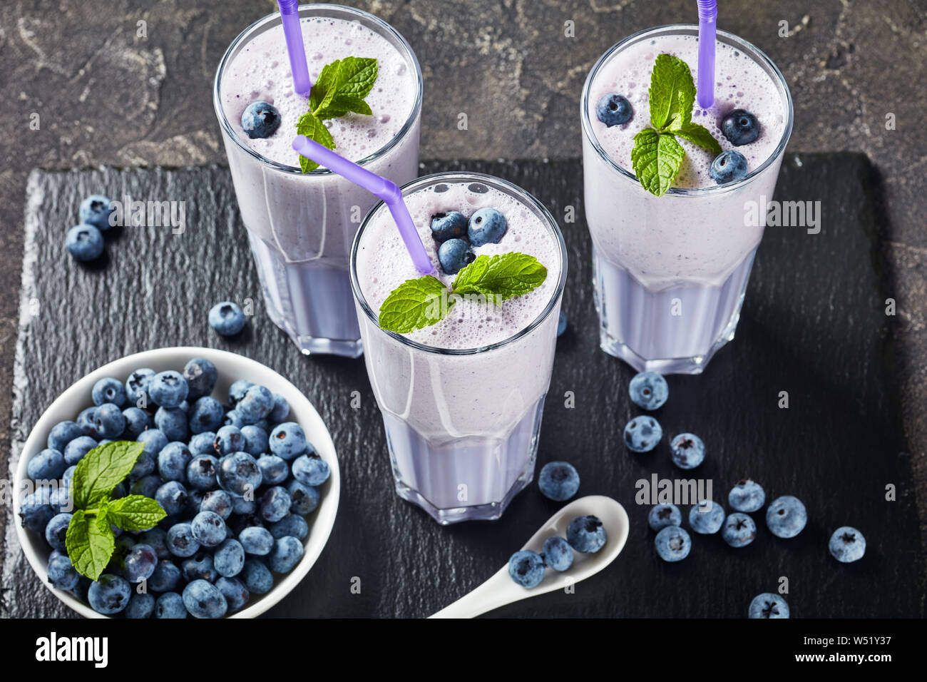 close-up of blueberry frothy milkshake of coconut milk in three glasses ...