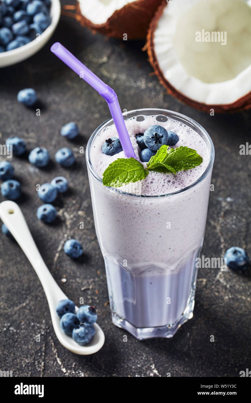 close-up of blueberry frothy milkshake of coconut milk in a glass with ...