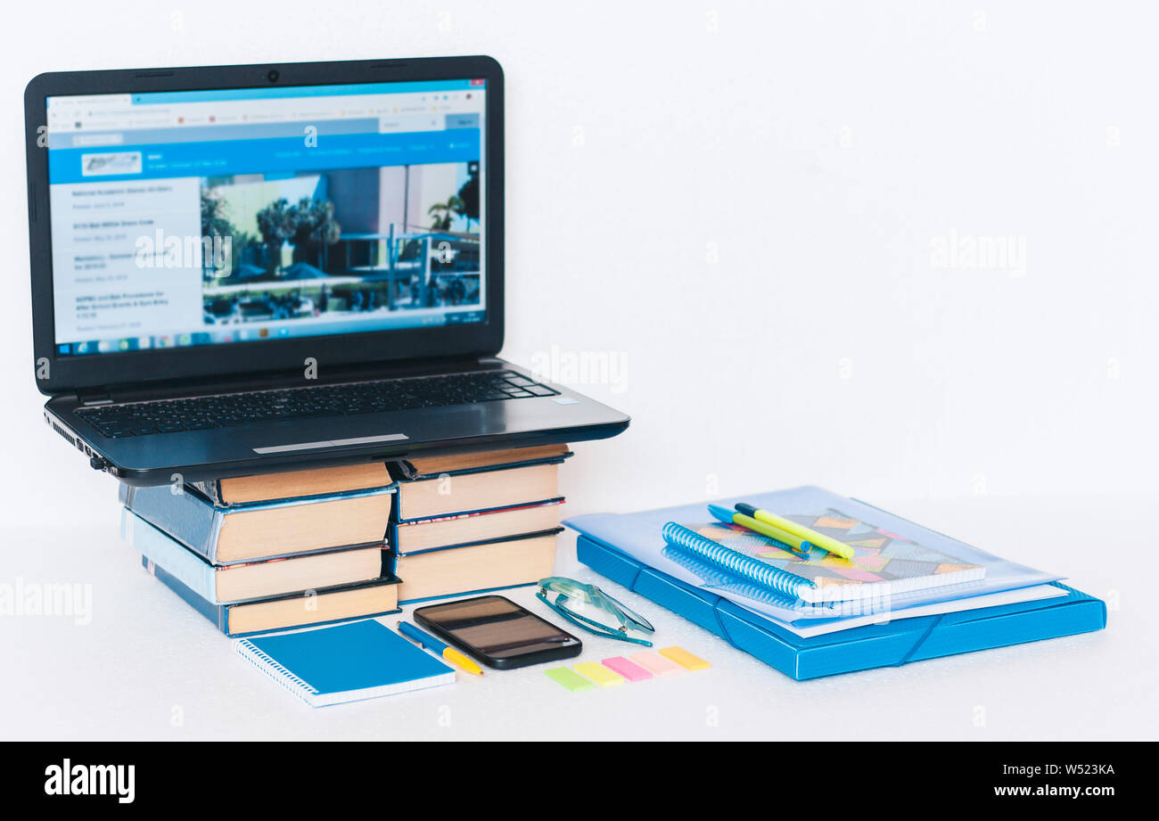 Laptop, smartphone, stack of books, notebook and pens on white wooden ...