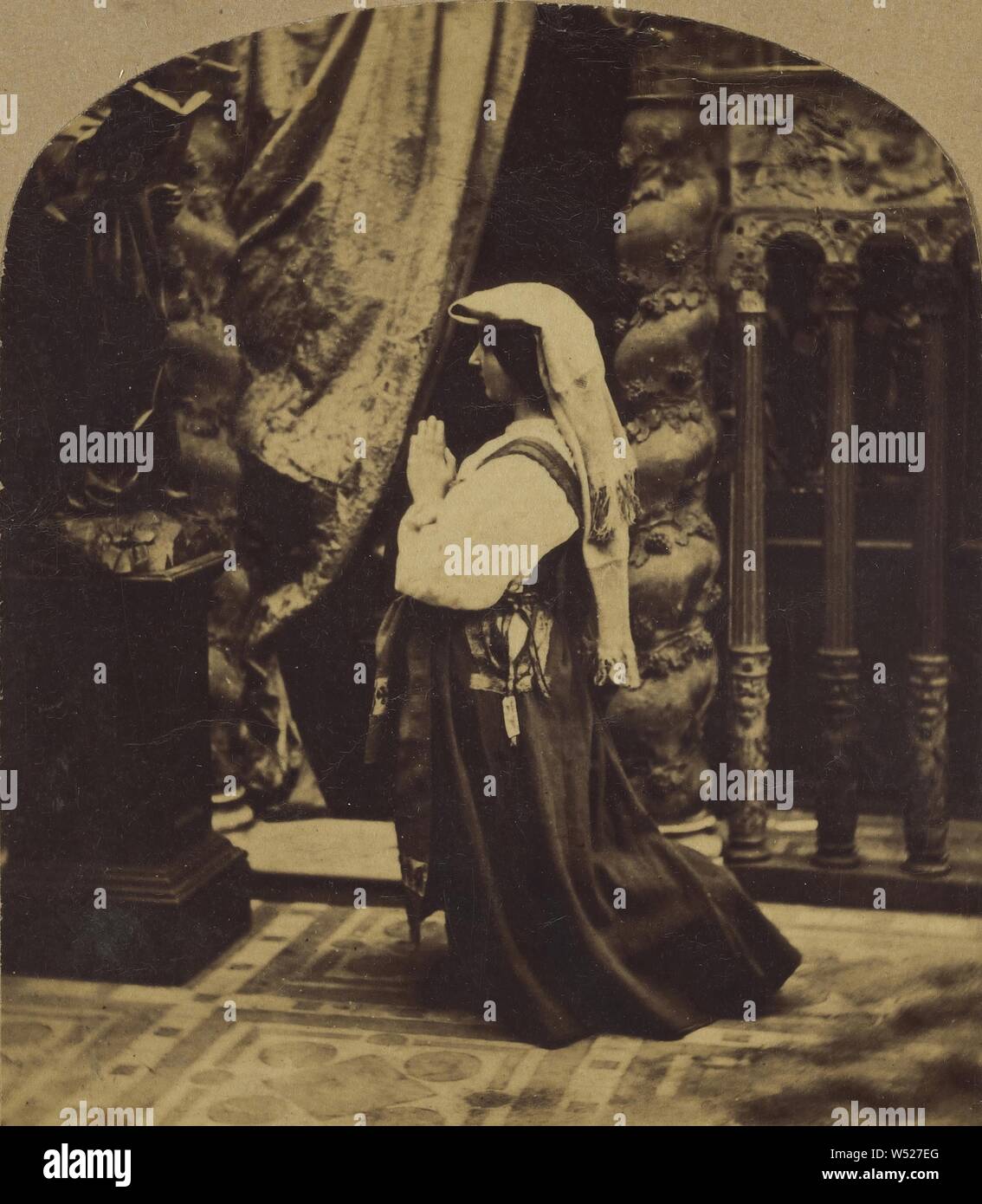 Pious woman with hands in prayer-like position kneeling in profile ...