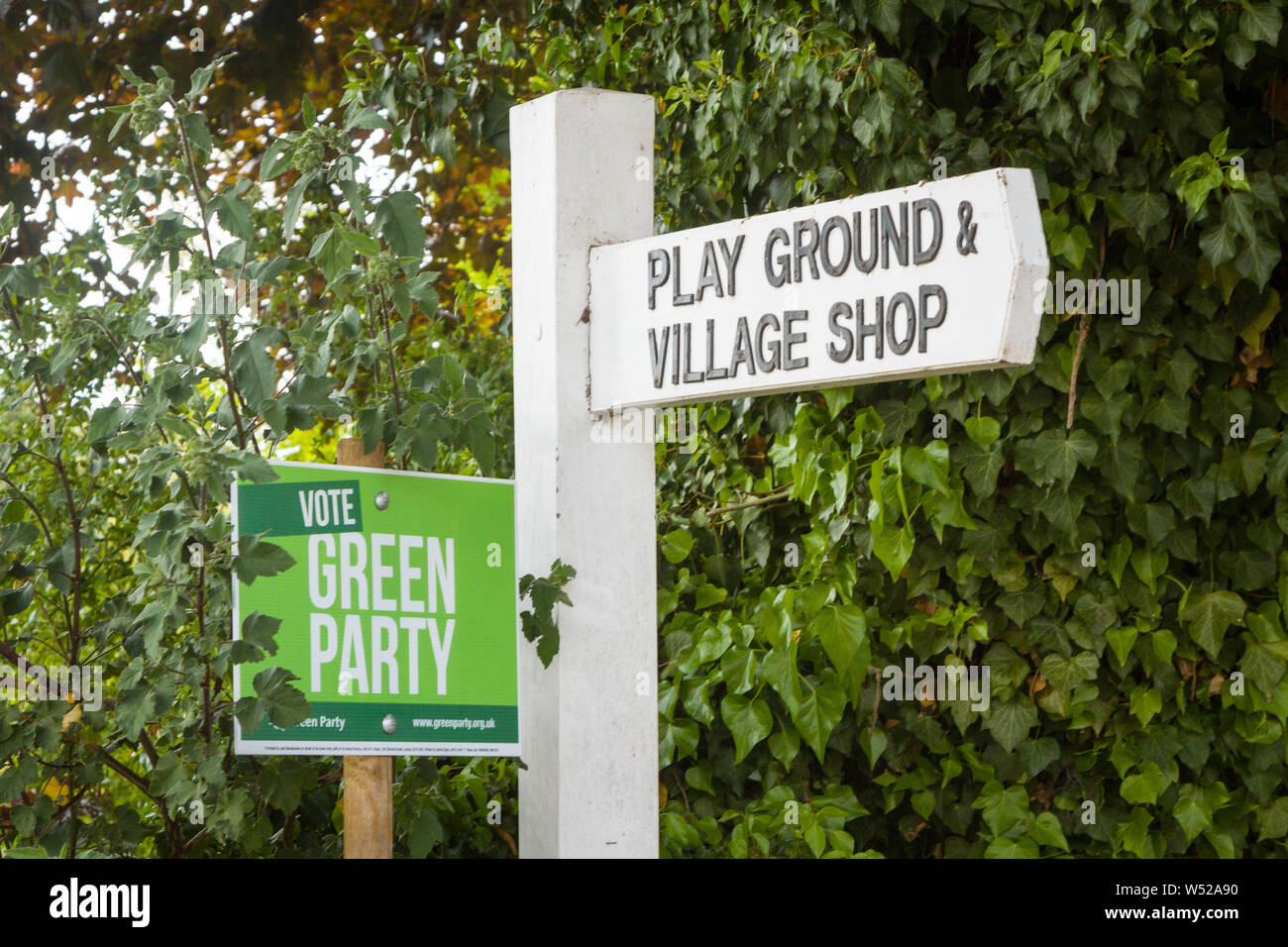 A Green Party election sign attached to a wooden sign for the village ...