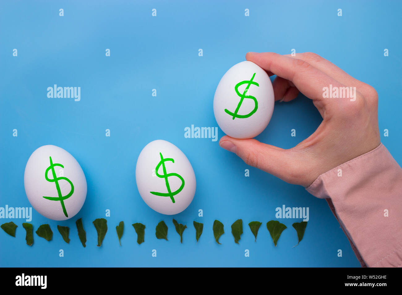 Eggs with dollar simbol on blue background Stock Photo - Alamy