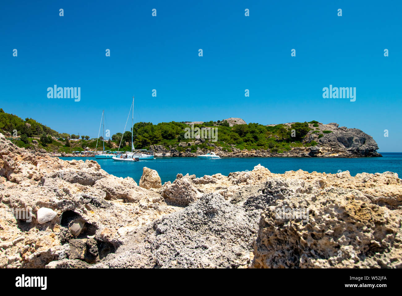 A bay on the island of Rhodes with sailing ships and rocks in the ...