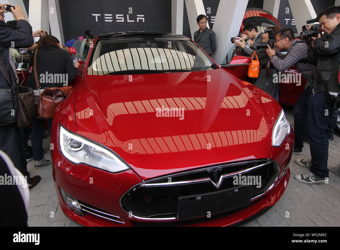 --FILE--People look at or take photos of a Tesla Model S electric car ...