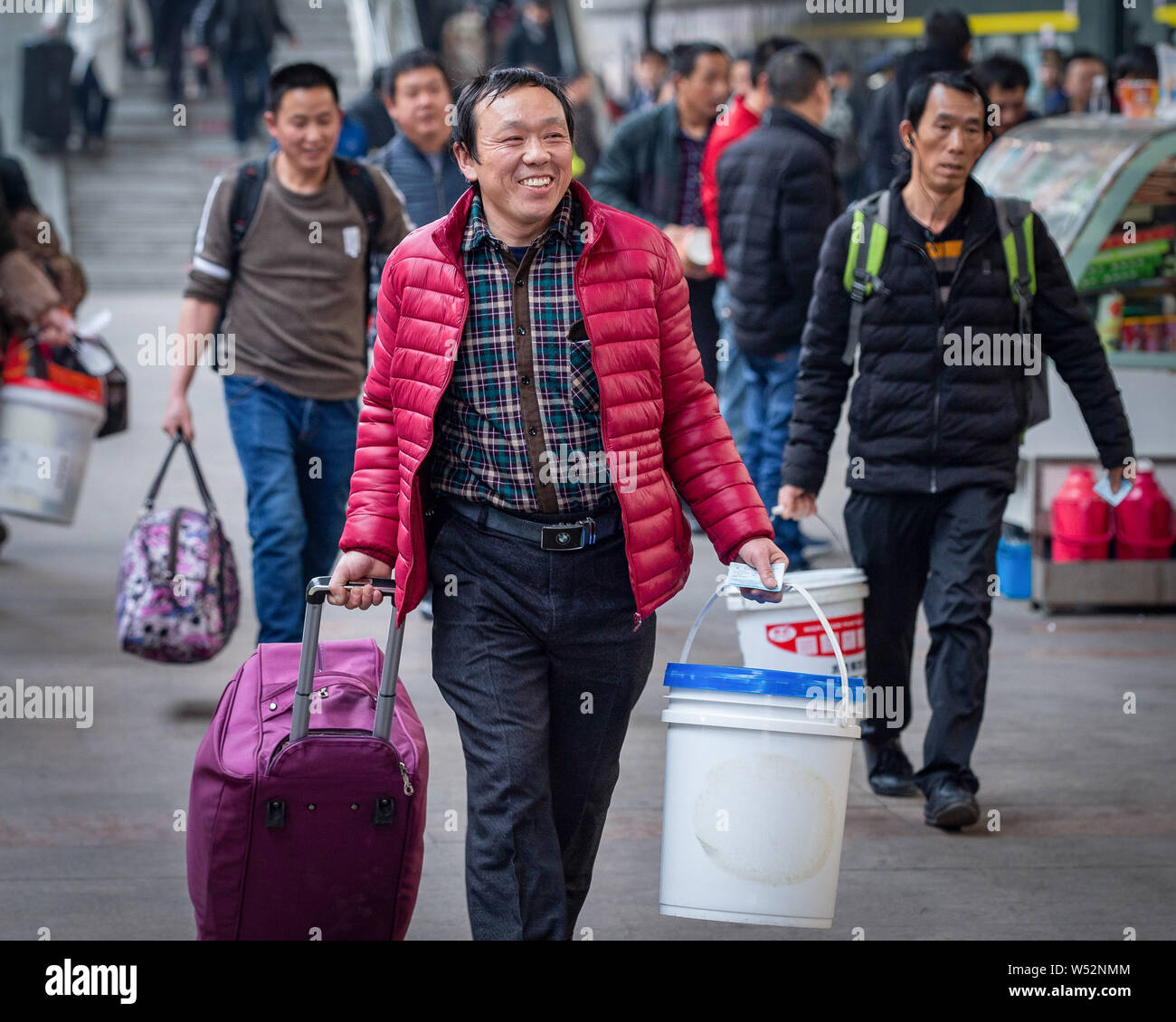Chinese passengers carry their luggage with plastic buckets as they are ...