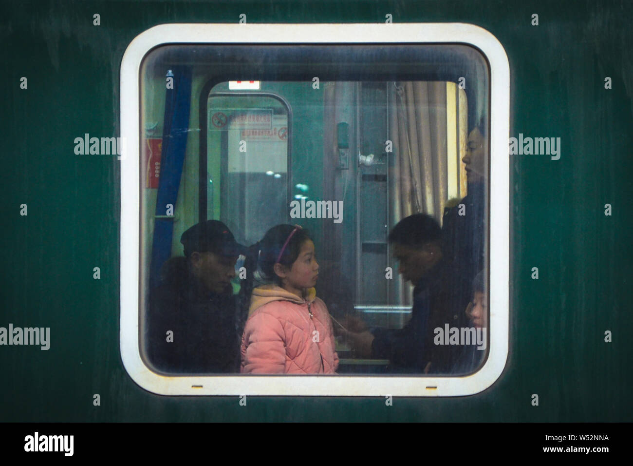 Chinese passengers are seen through a window of a train on their way ...