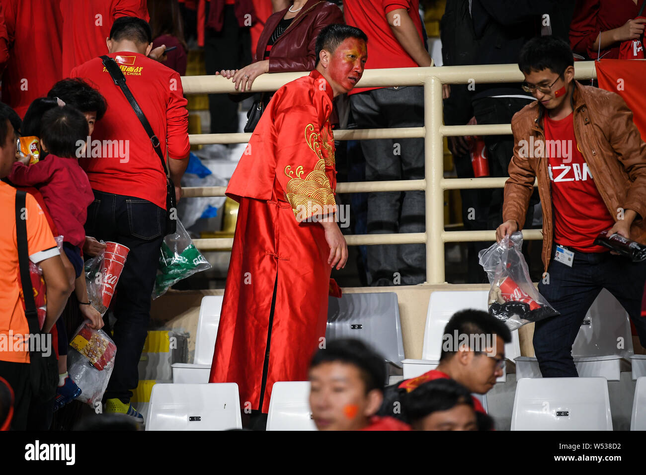 Chinese football fans clean the stadium's stand after China was ...