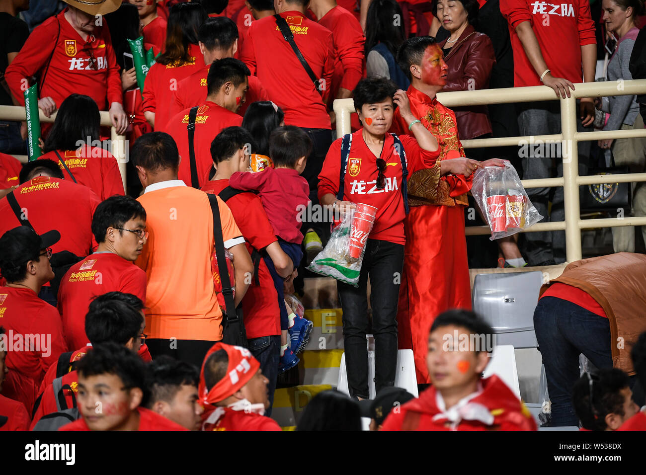 Chinese football fans clean the stadium's stand after China was ...
