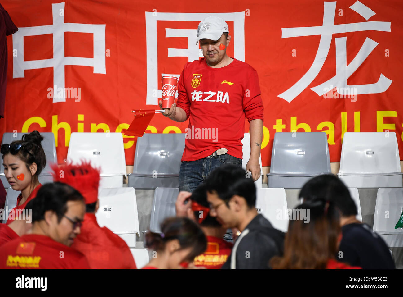 Chinese football fans clean the stadium's stand after China was ...