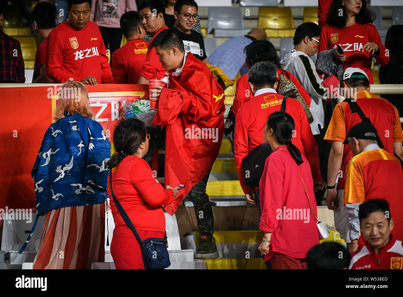 Chinese football fans clean the stadium's stand after China was ...