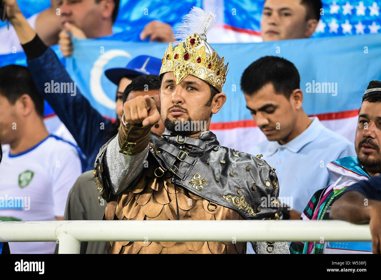 A Uzbek fan dressed in traditional costumes and wearing a crown poses ...