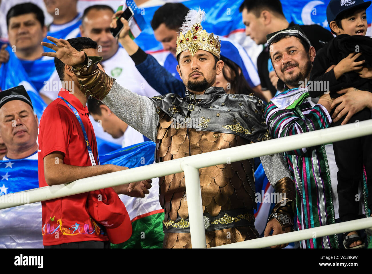 A Uzbek fan dressed in traditional costumes and wearing a crown poses ...