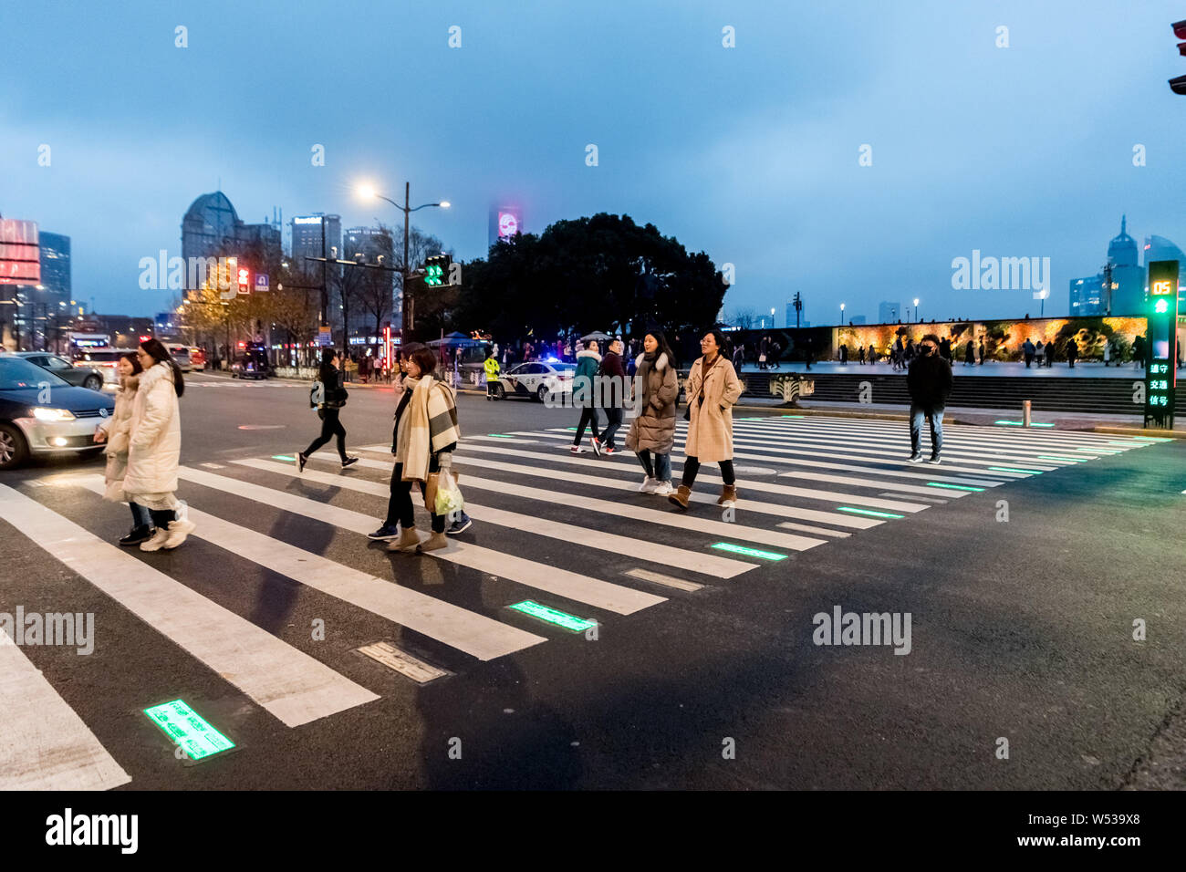 Pedestrians walk across a zebra crossing illuminated by LED lights in ...