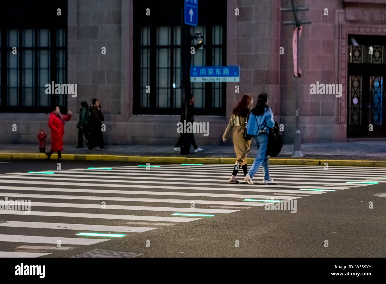 Pedestrians walk across a zebra crossing illuminated by LED lights in ...
