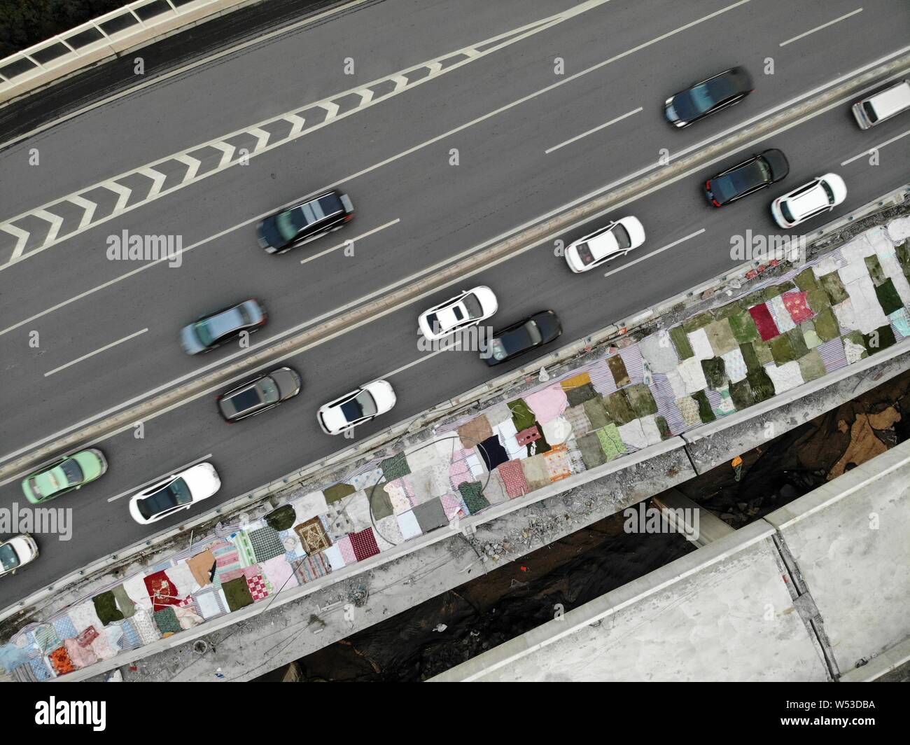 Cars pass by a newly-constructed ramp covered with quilts on an ...