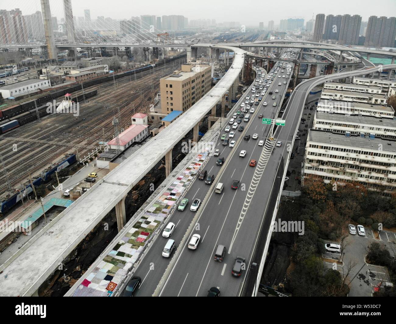 Cars pass by a newly-constructed ramp covered with quilts on an ...