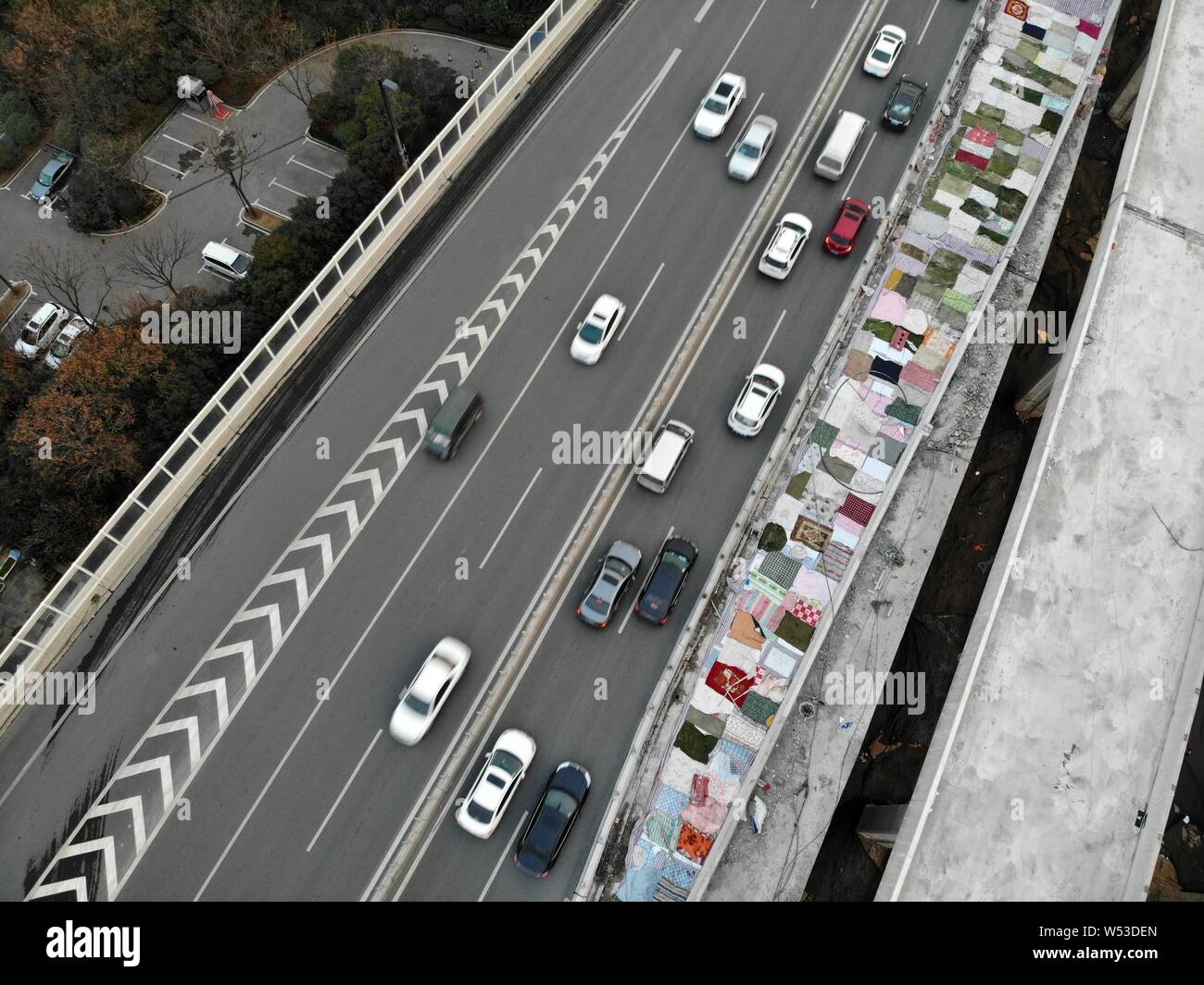 Cars pass by a newly-constructed ramp covered with quilts on an ...