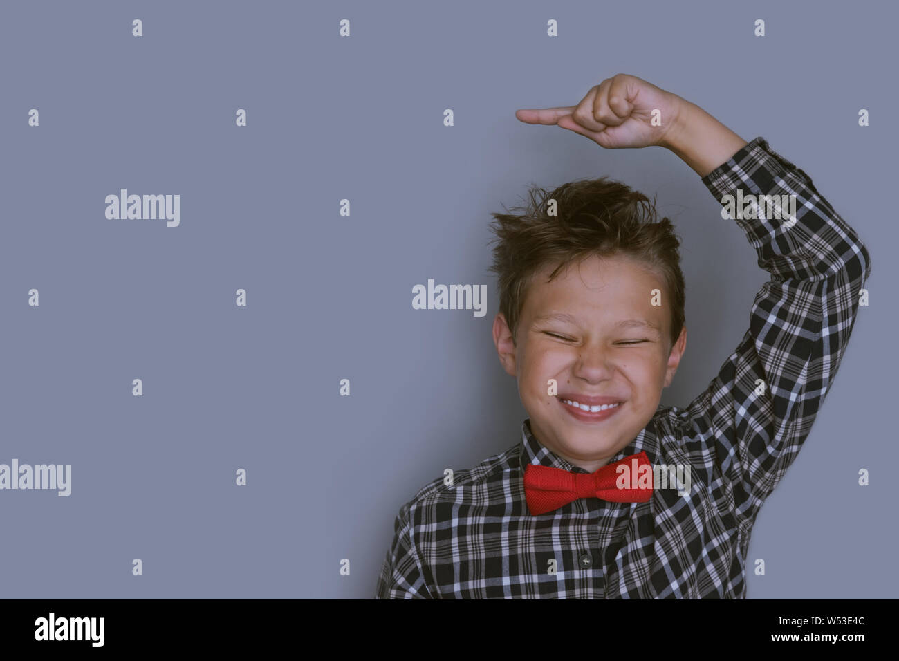 Young schoolchild pointing up portrait. Preteen schoolboy with glasses ...