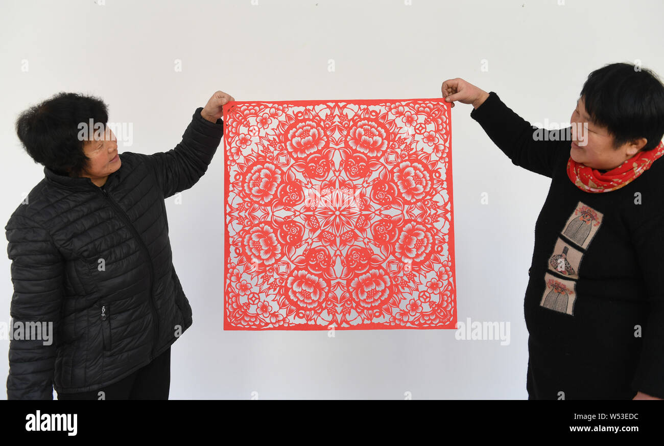 Chinese folk artist Li Yinjie, right, shows a paper-cutting artwork ...