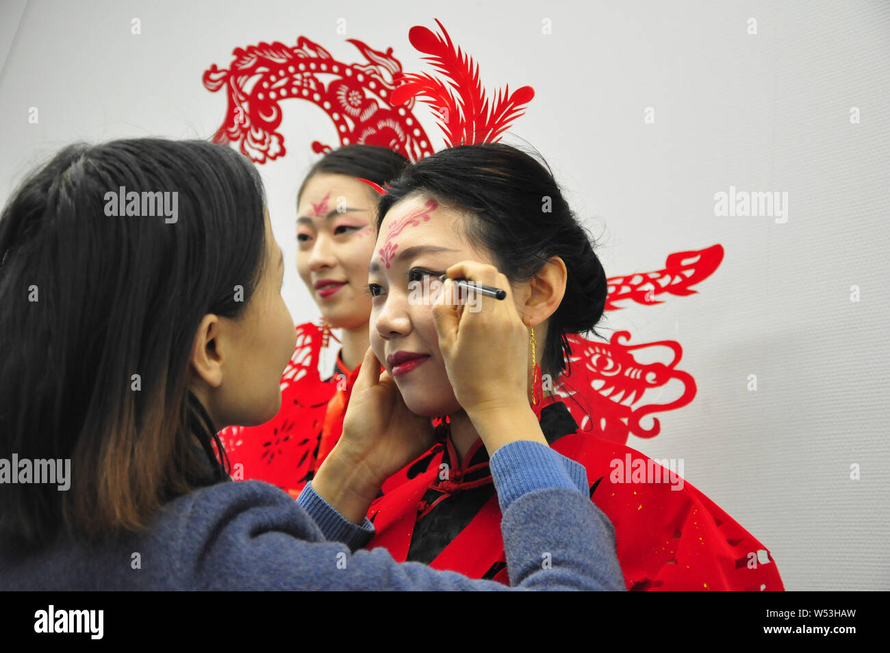 Chinese craftswoman Liang Ying helps a model finish make-up after ...