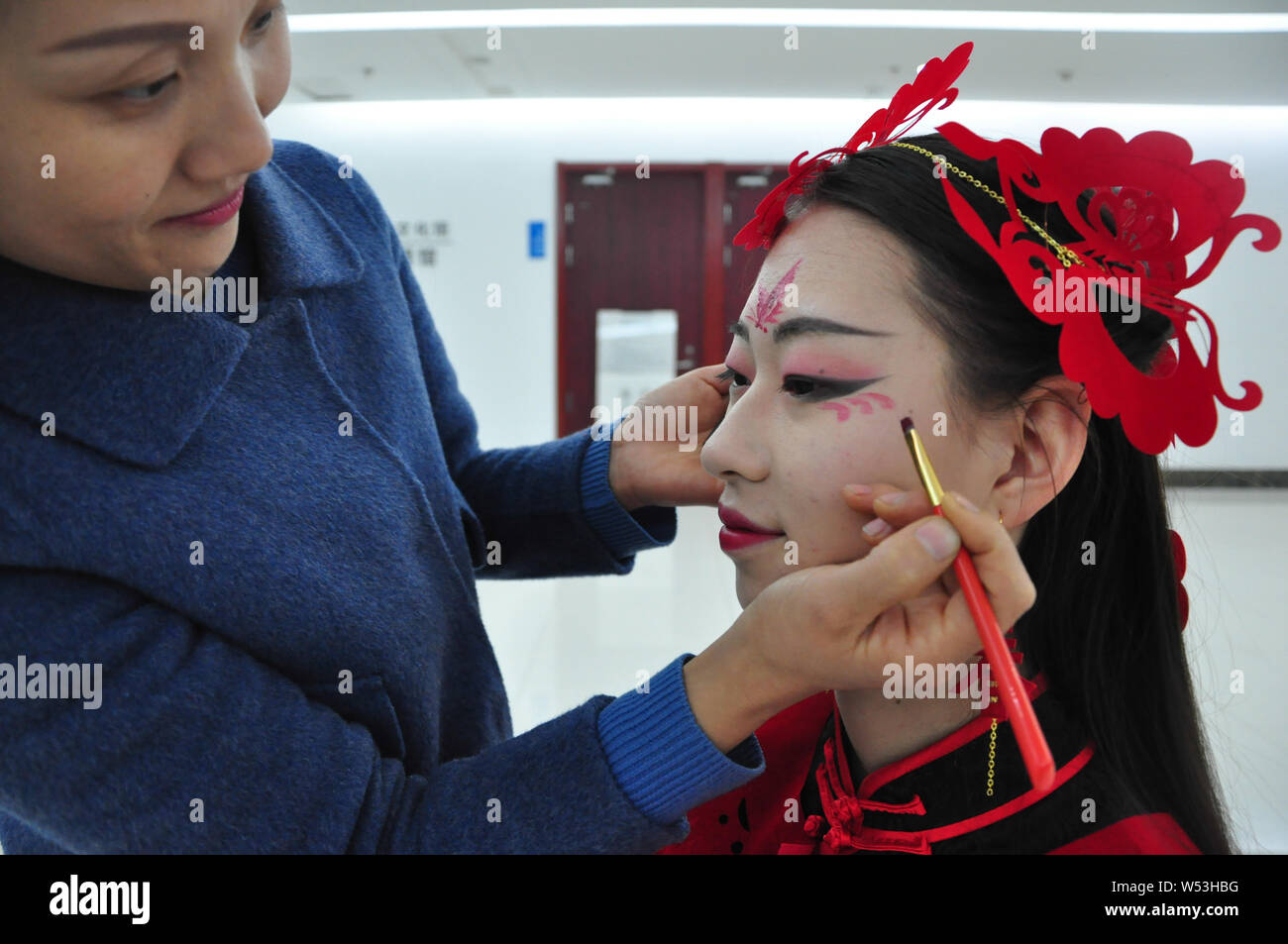 Chinese craftswoman Liang Ying helps a model finish make-up after ...