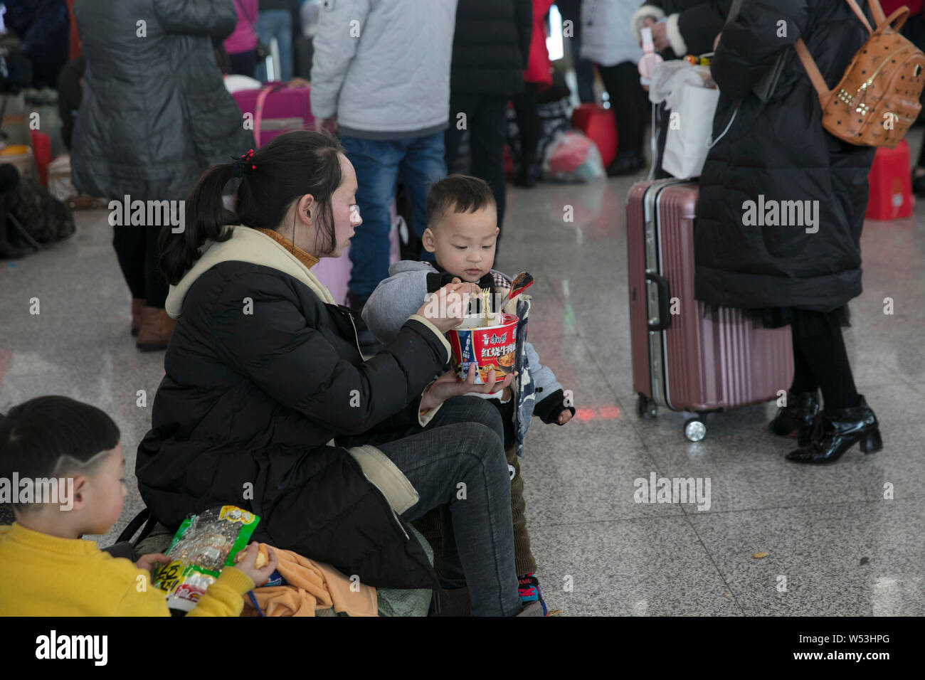 A child eats instant noodles as he and his mother wait for their train ...