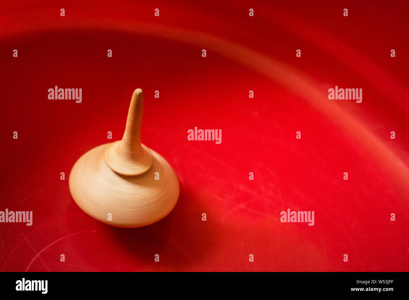 A close-up of a wooden spinning top on a red background Stock Photo - Alamy