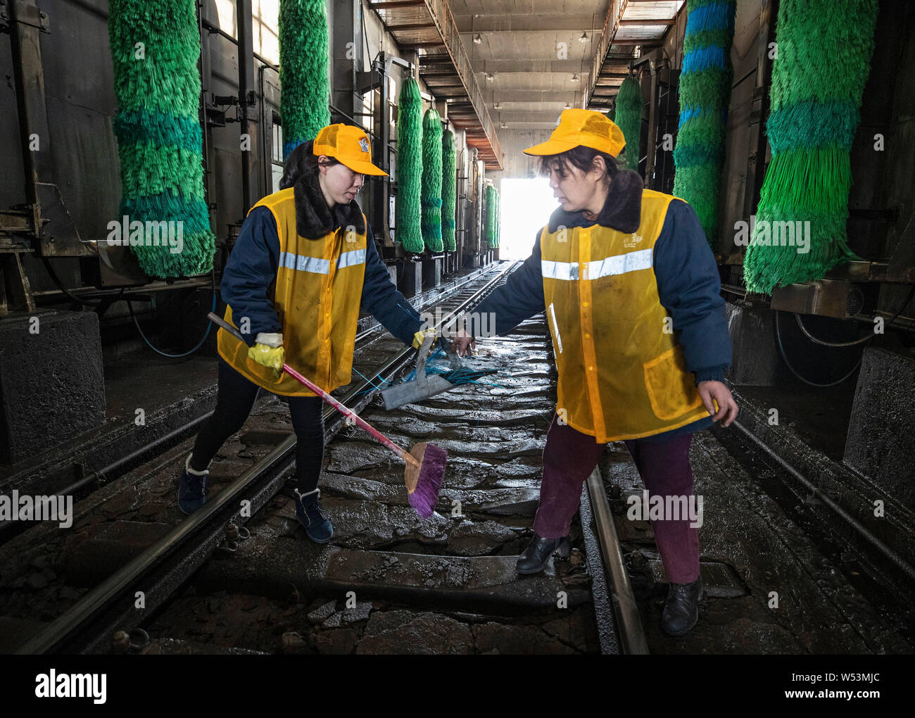 Female Chinese workers deice and clean a railway train in preparation ...