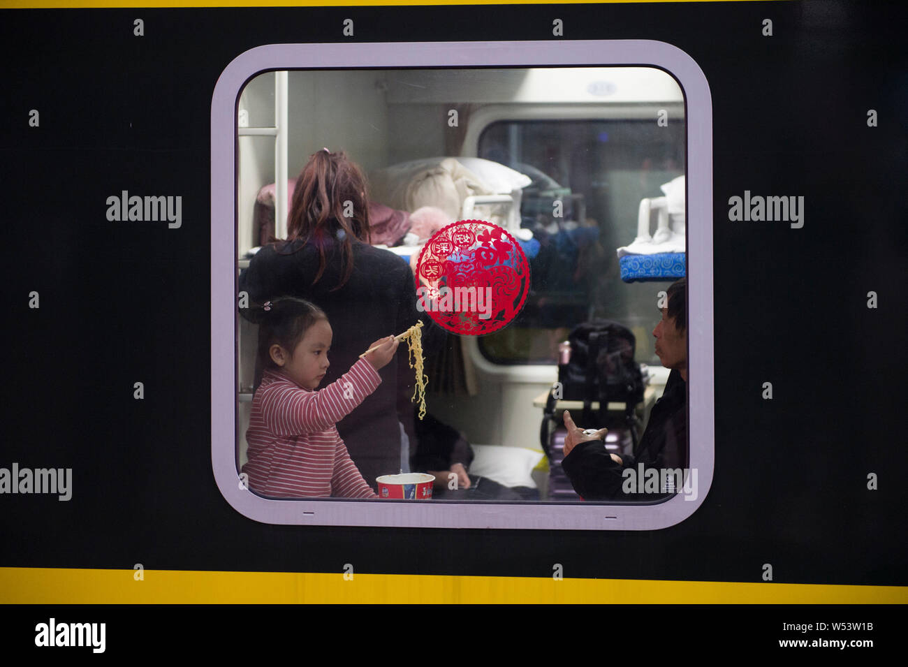 A little Chinese girl eats instant noodle on the train on her way back ...